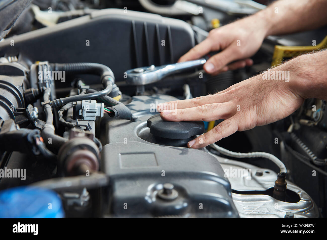 Hand with tool on car engine during inspection or maintenance in a ...