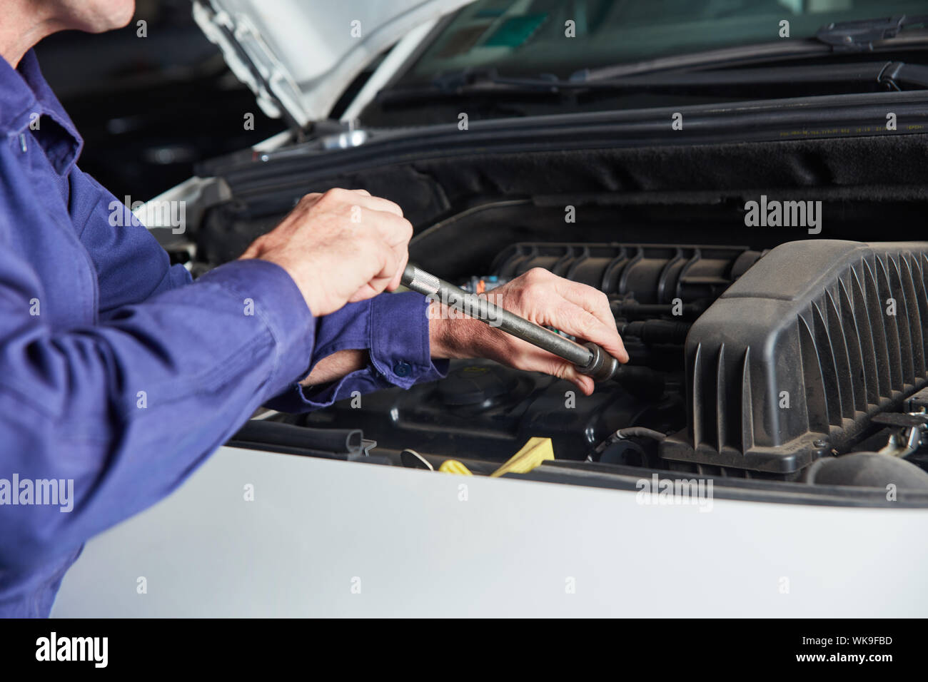 Mechanic at auto inspection or tuning screws with tool on engine Stock ...