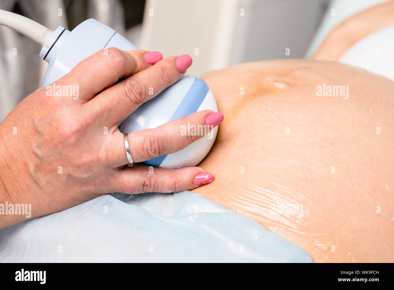 Sonographer scanning young pregnant woman's abdomen with ultrasonic ...