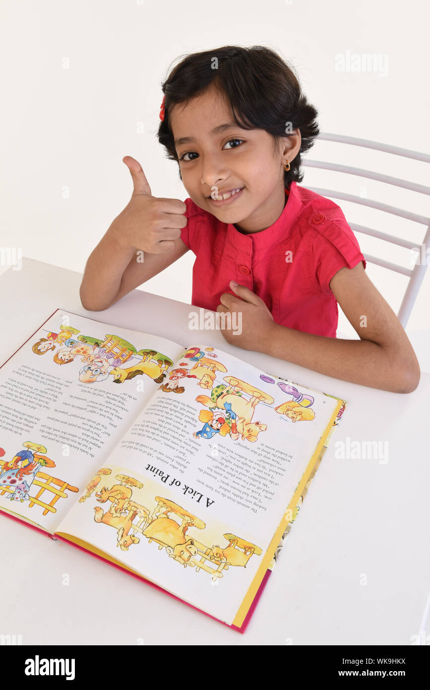 High angle view of girl reading a book and showing thumbs up sign Stock ...