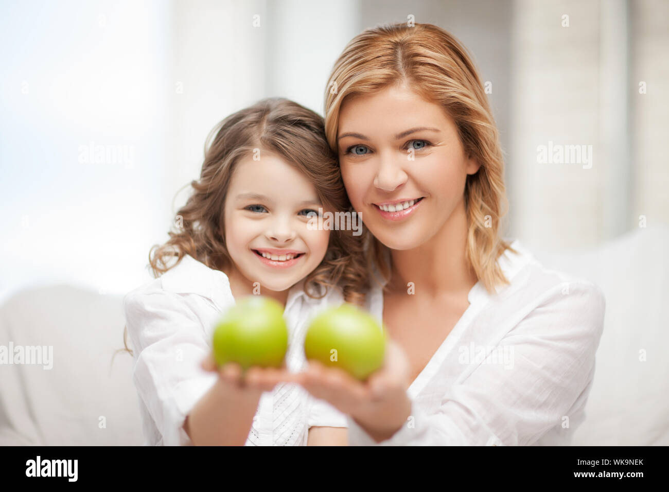 bright picture of mother and daughter holding green apples Stock Photo ...