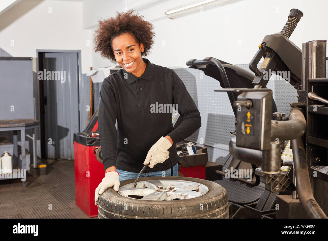 Cheerful African woman as a car mechanic or mechatronics in tire ...