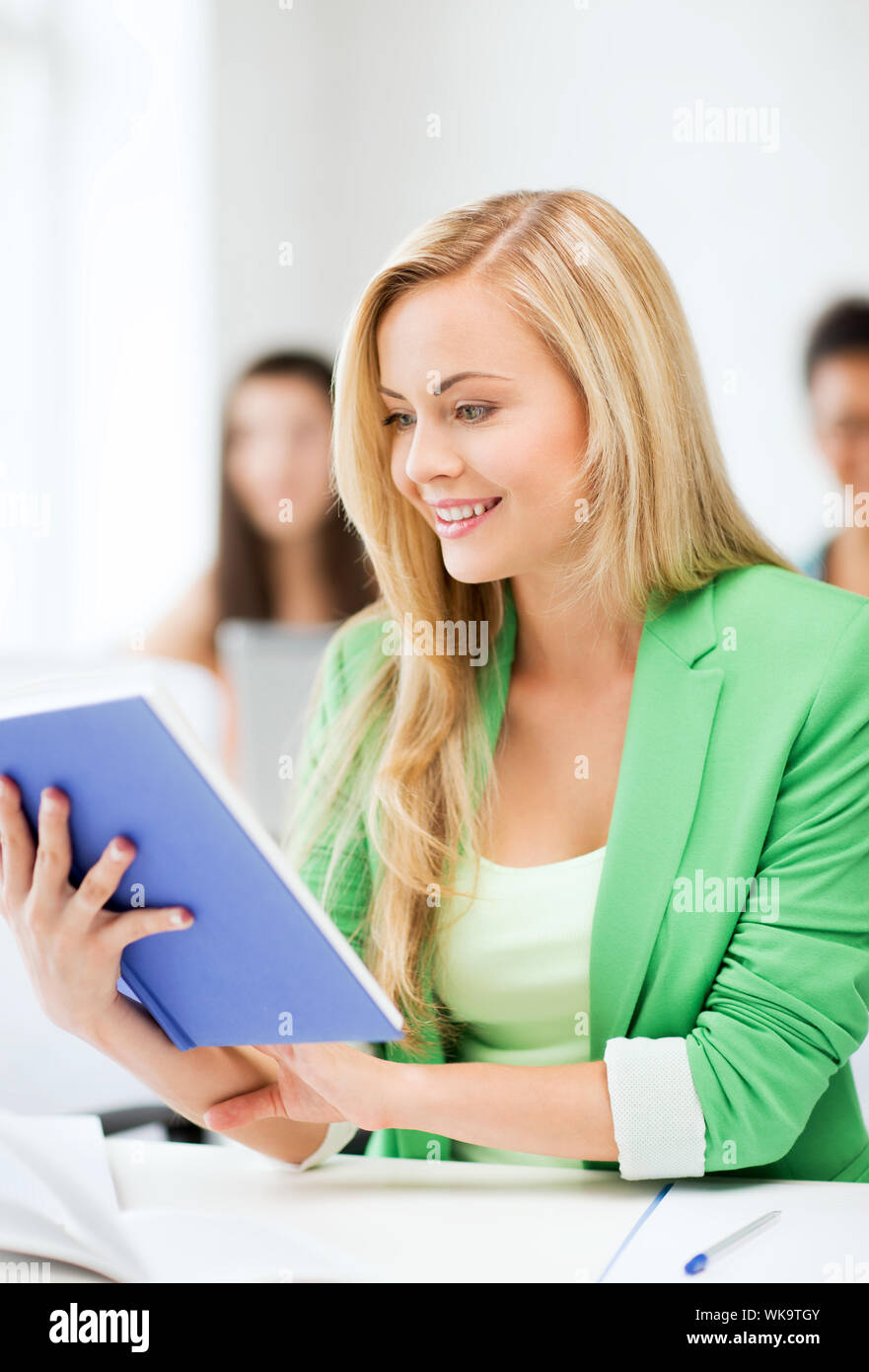 education concept - smiling young girl reading book at school Stock ...