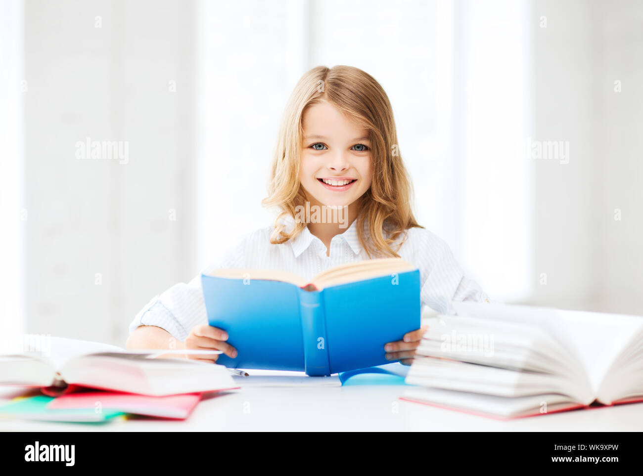 education and school concept - little student girl studying and reading ...