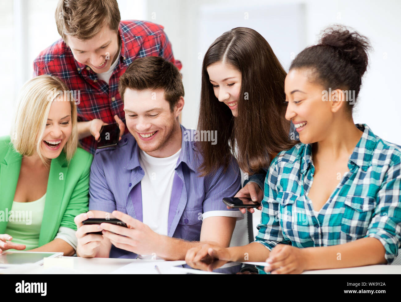 education, technology and internet - smiling students looking at ...