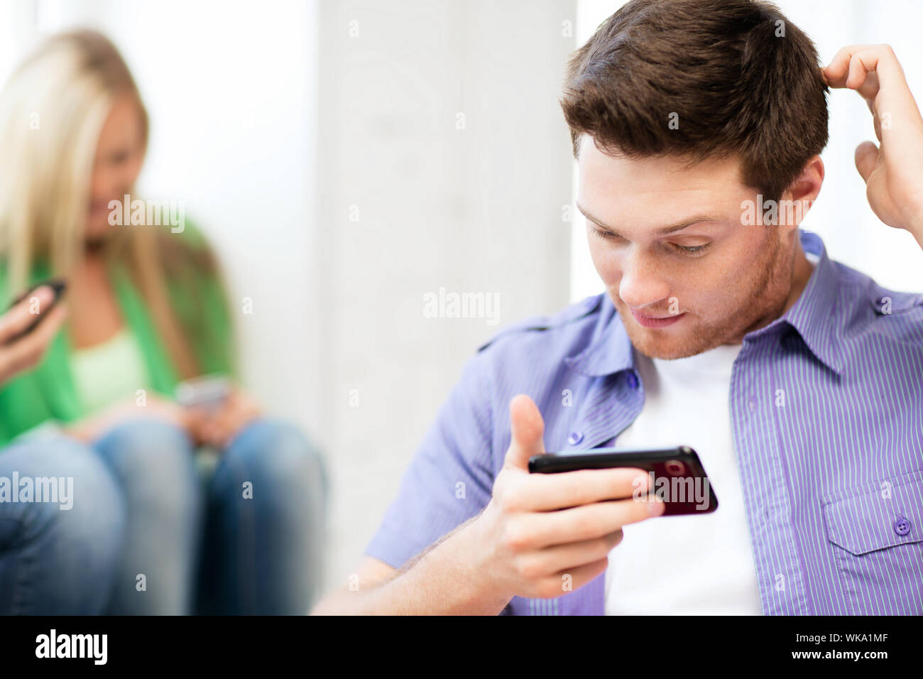 student looking at phone and writing something Stock Photo - Alamy