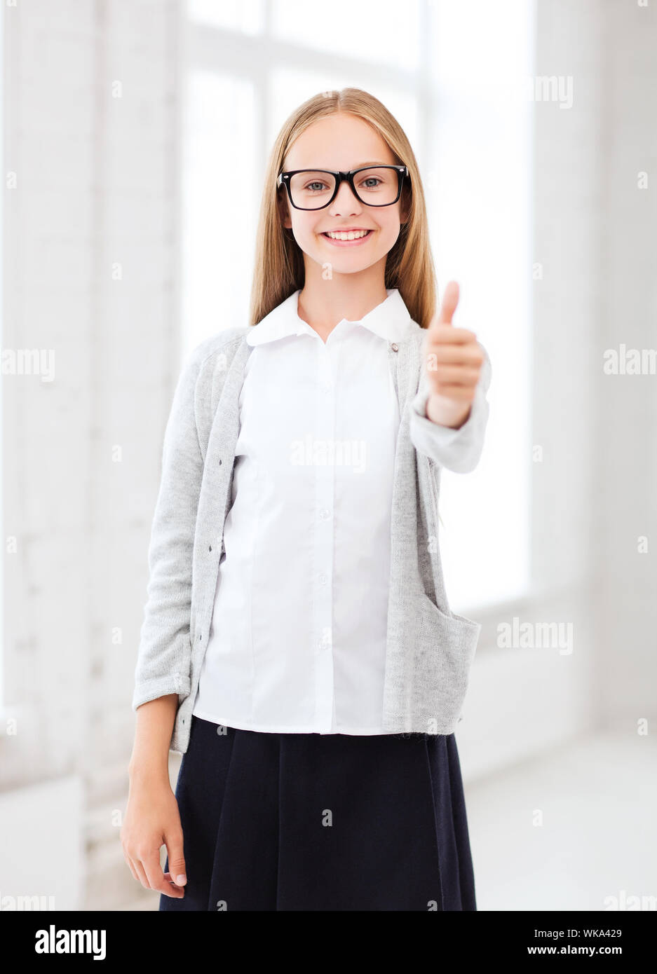 education and school concept - little student girl showing thumbs up at ...