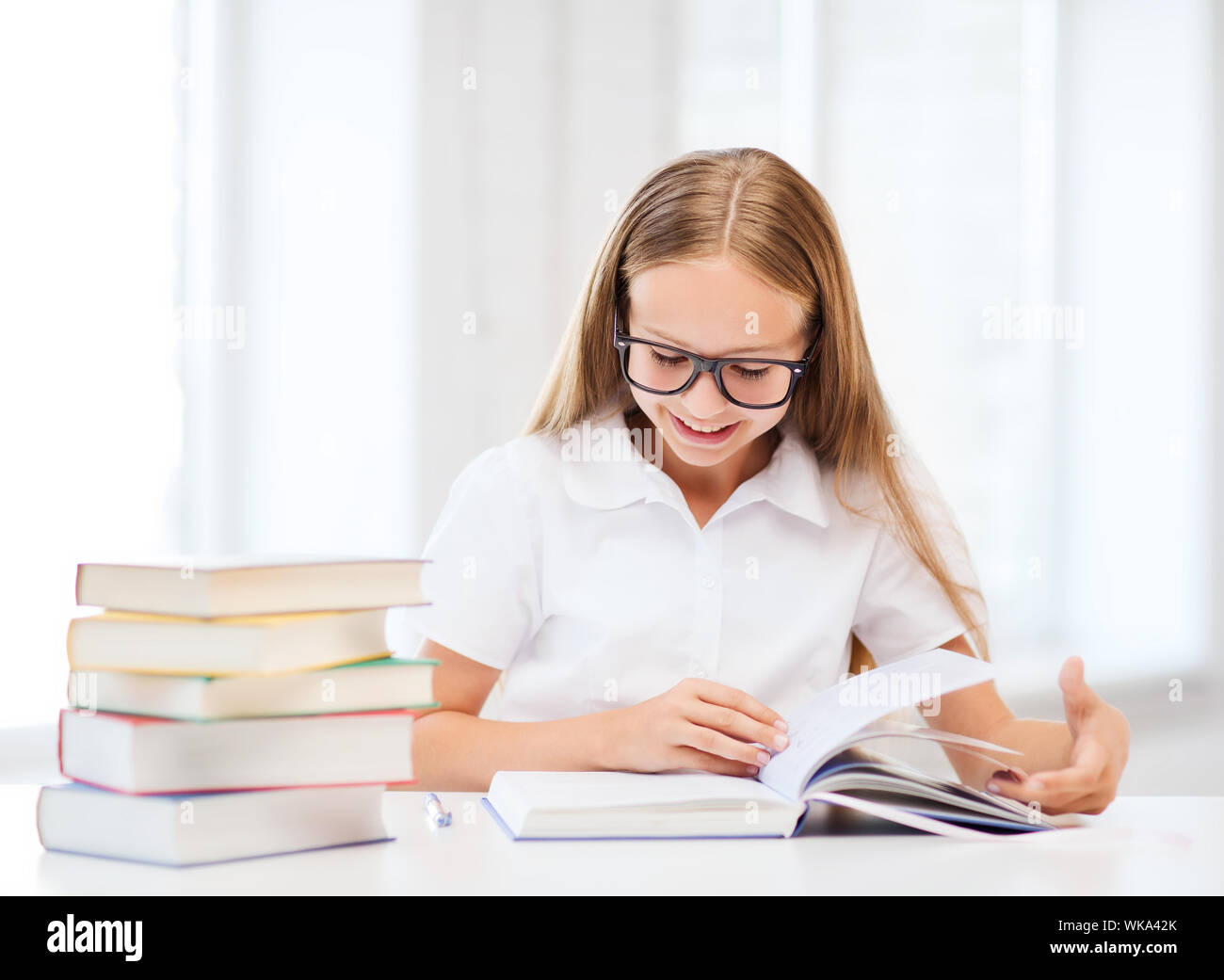 education and school concept - little student girl studying and reading ...