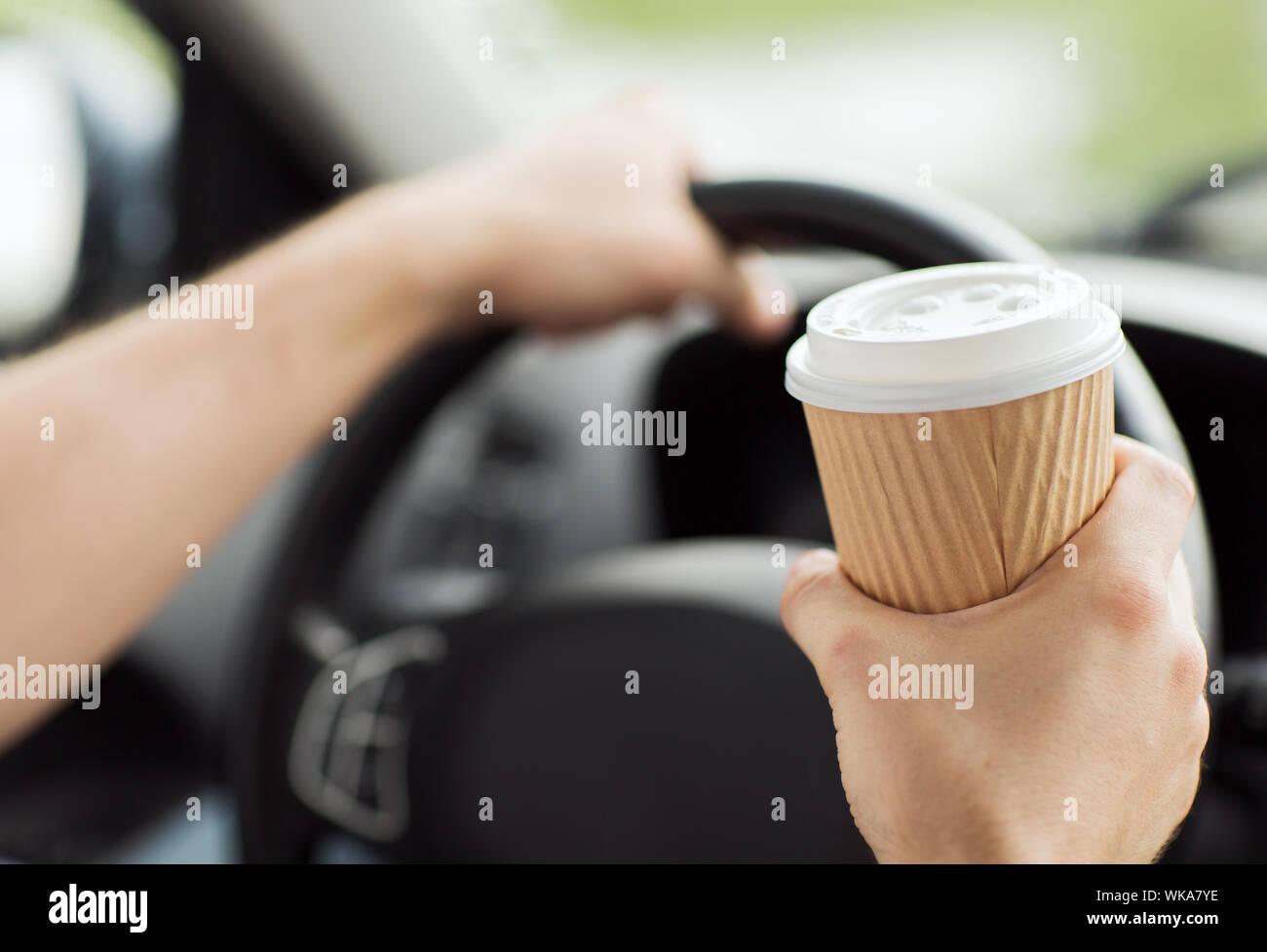 transportation and vehicle concept - man drinking coffee while driving ...