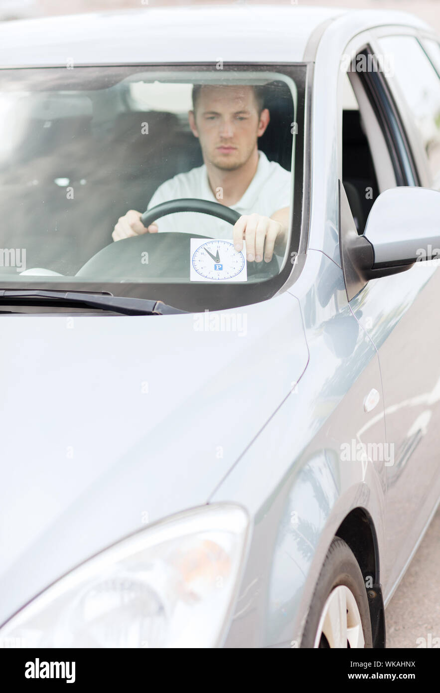 man placing parking clock on car dashboard Stock Photo - Alamy