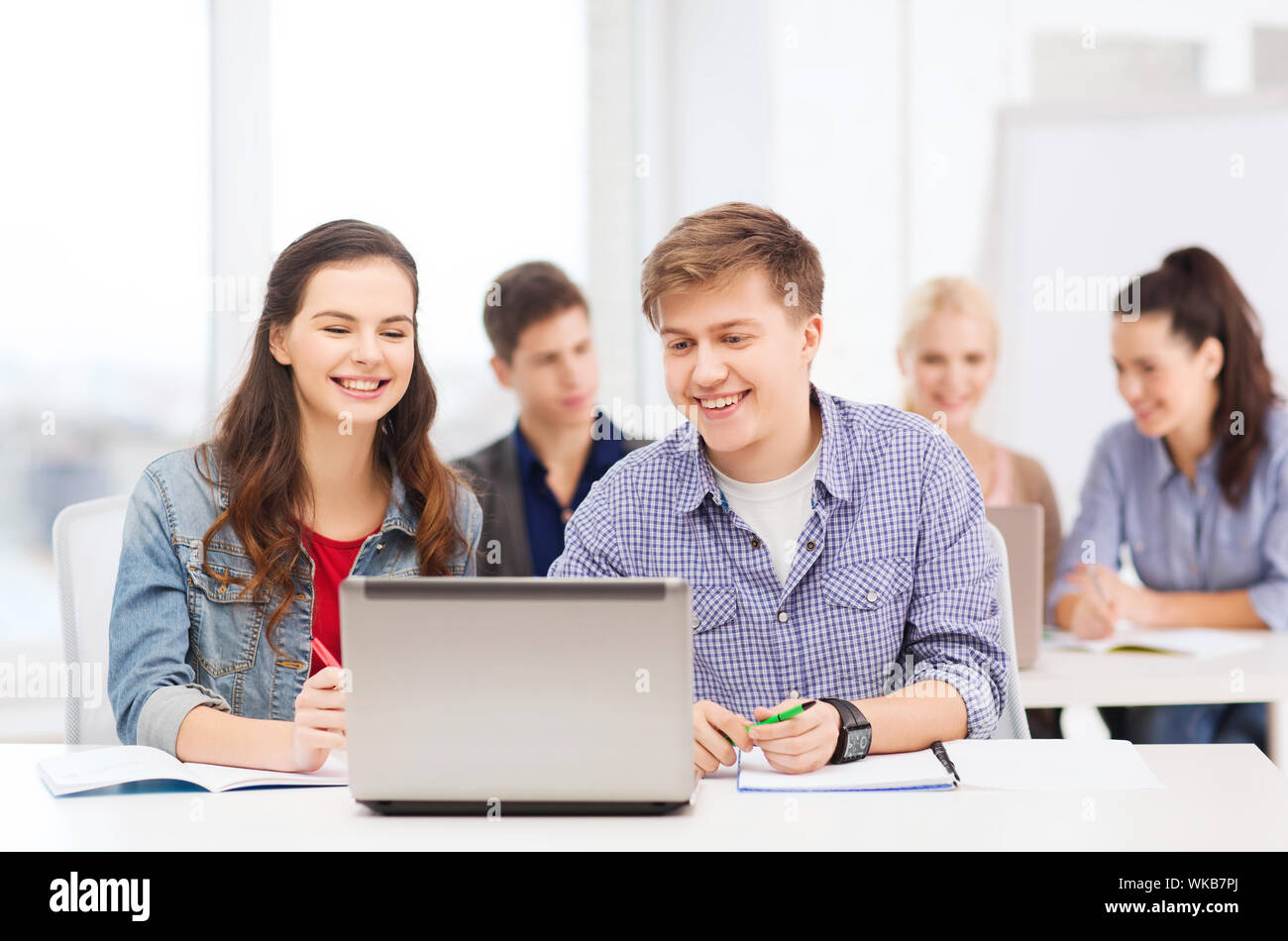 education, technology and internet concept - two smiling students with ...