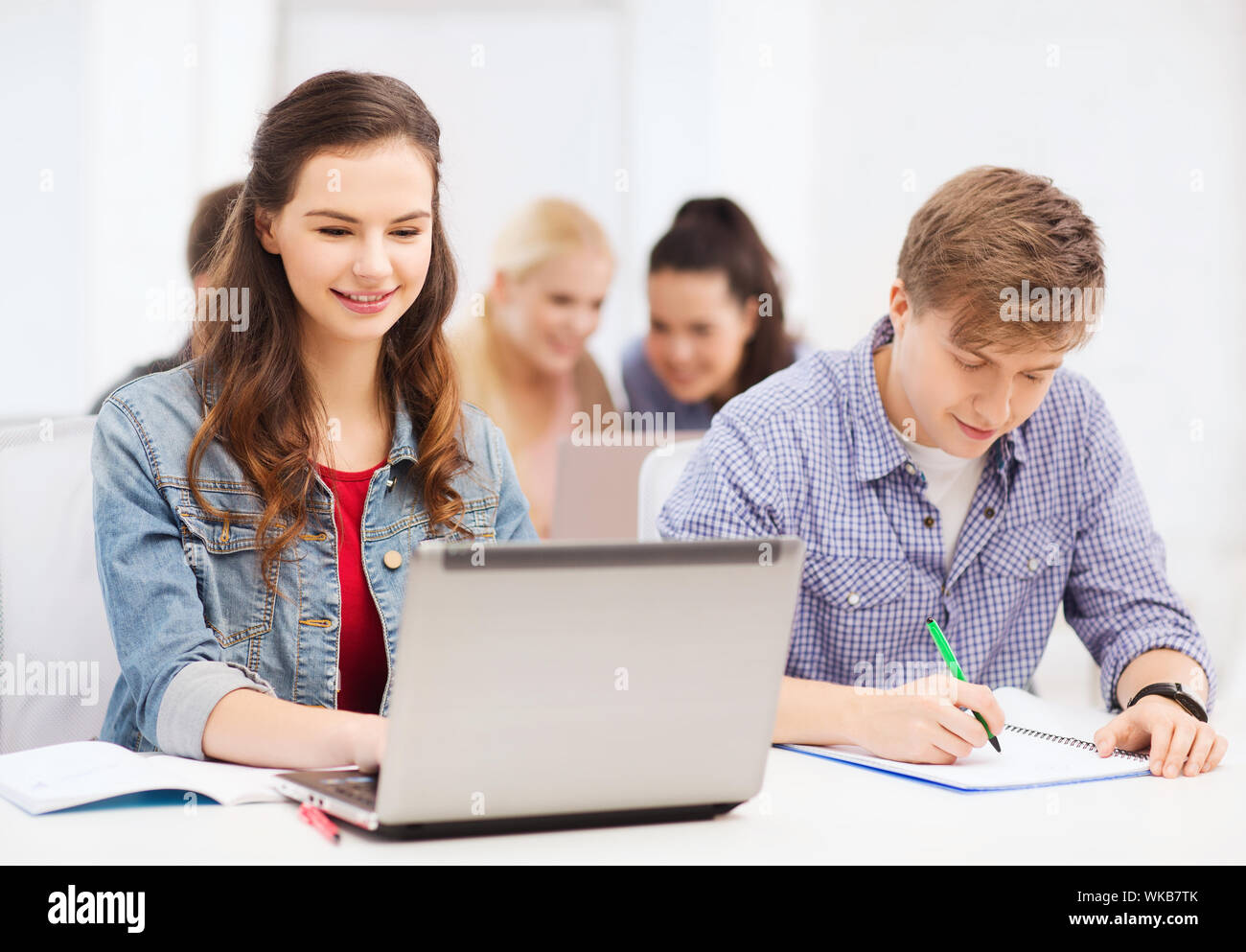 education, technology and internet concept - two smiling students with ...