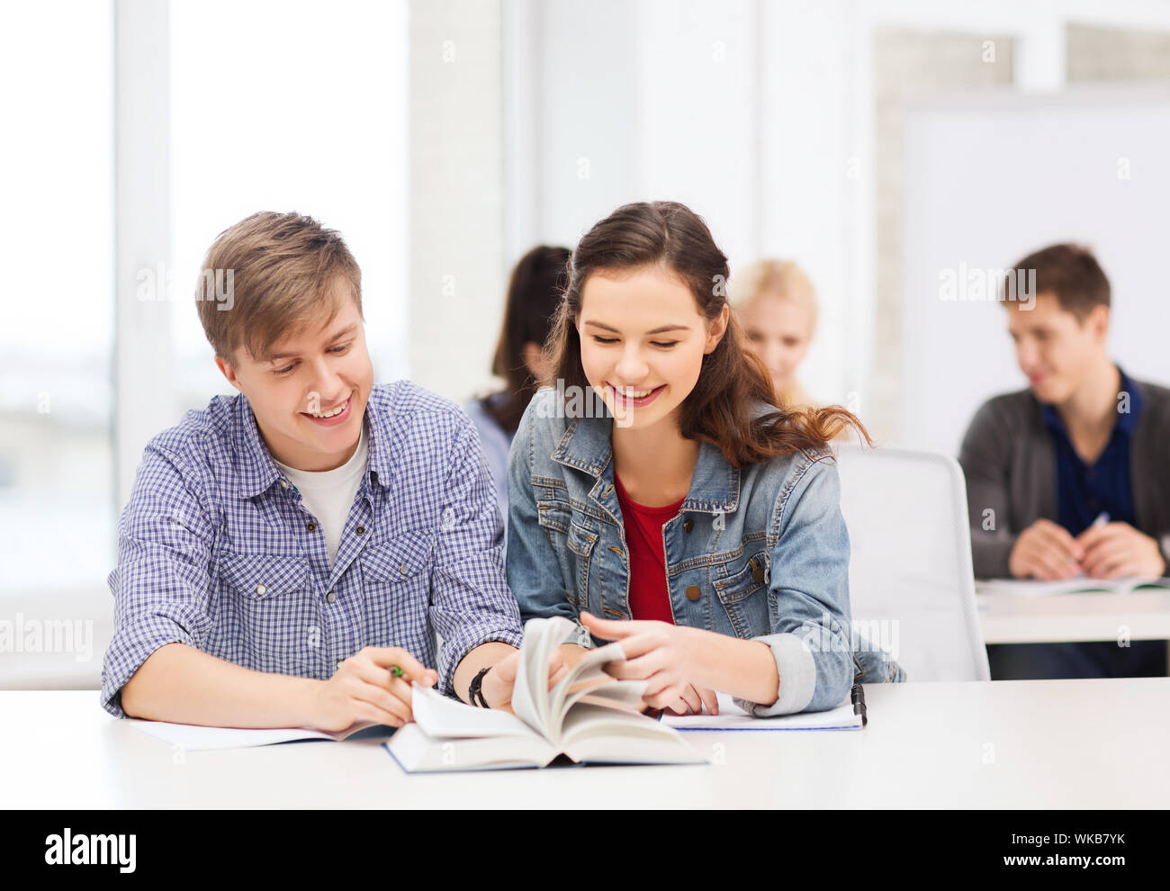 two teenagers with notebooks and book at school Stock Photo - Alamy