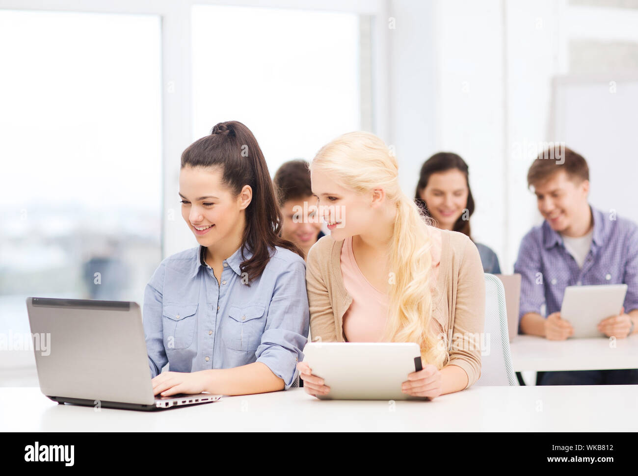education, technology and internet concept - two smiling girl students ...