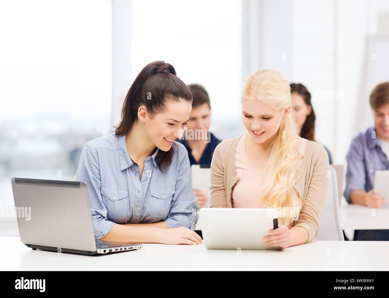 education, technology and internet concept - two smiling students with ...