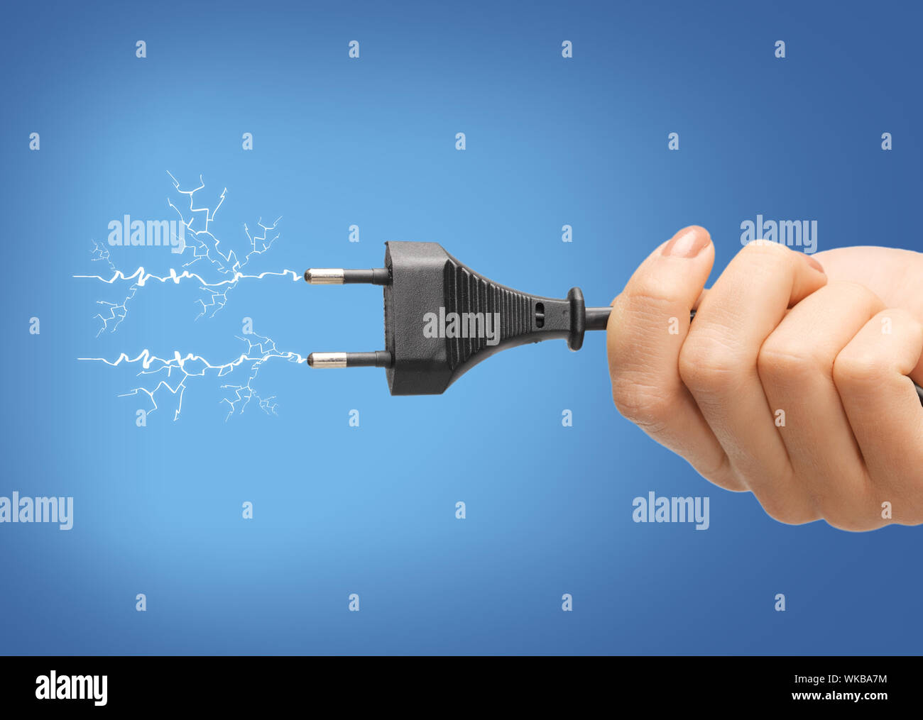 electricity concept - close up of hand holding black electrical plug ...