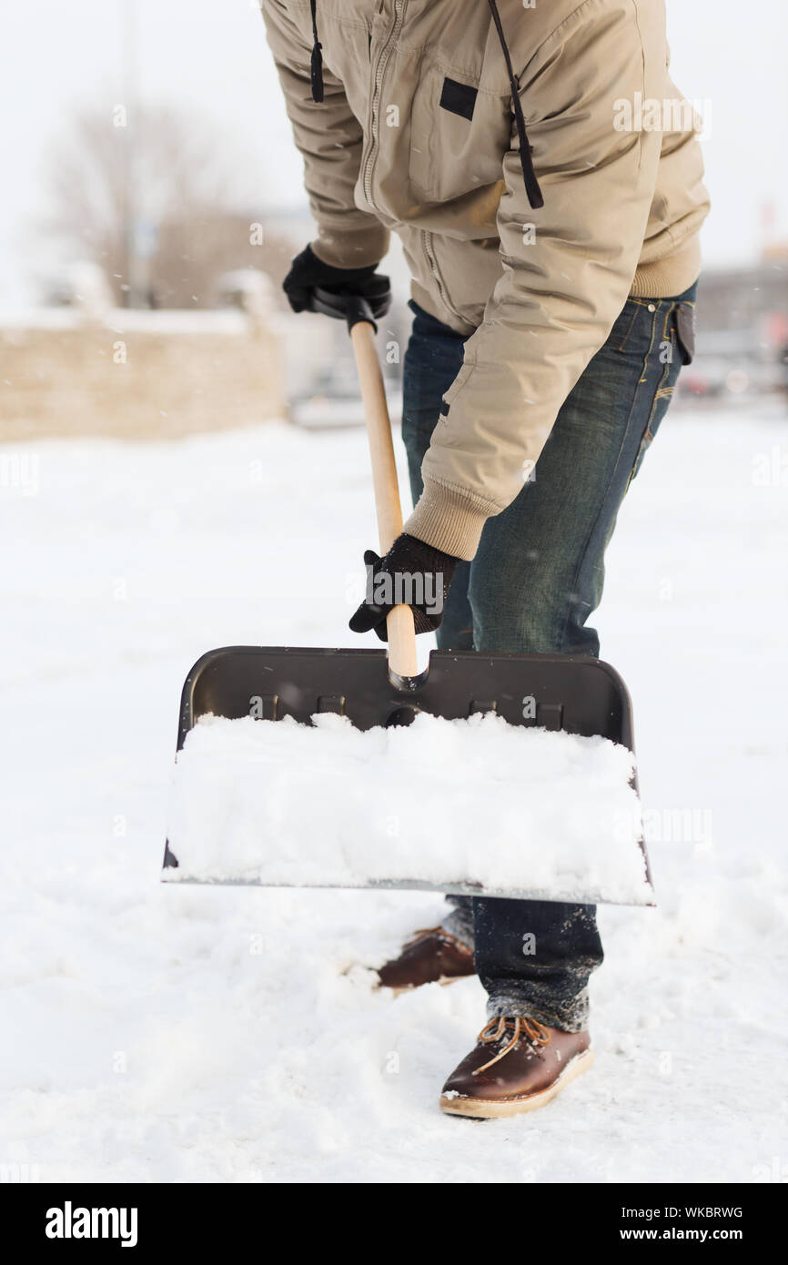 winter and cleaning concept - closeup of man shoveling snow from ...