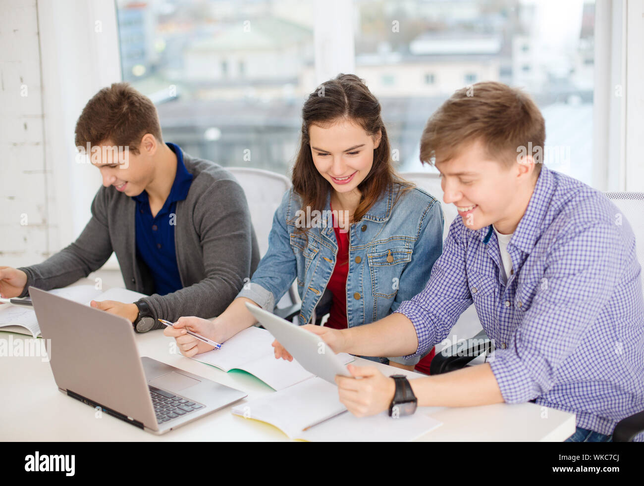 education, technology, school and internet concept - three smiling ...