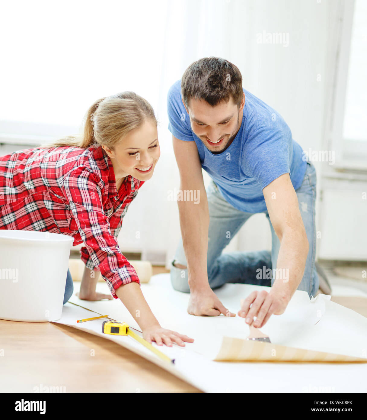 repair, building and home concept - smiling couple smearing wallpaper ...