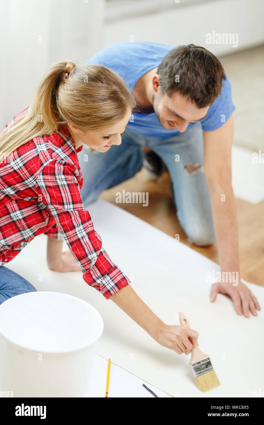 repair, building and home concept - smiling couple smearing wallpaper ...