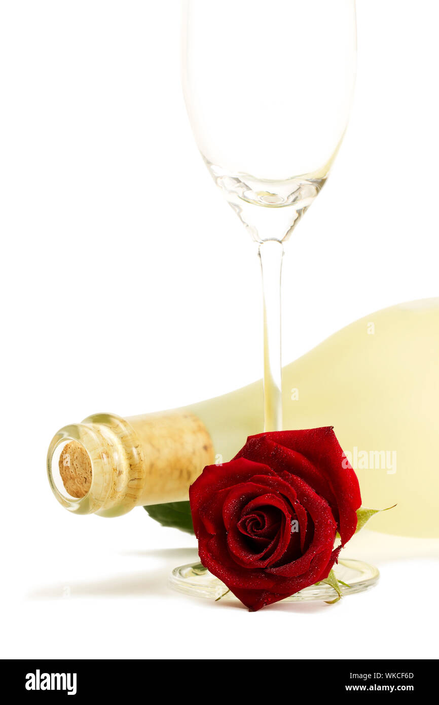 wet red rose with a dull prosecco bottle and a empty champagne glass on ...