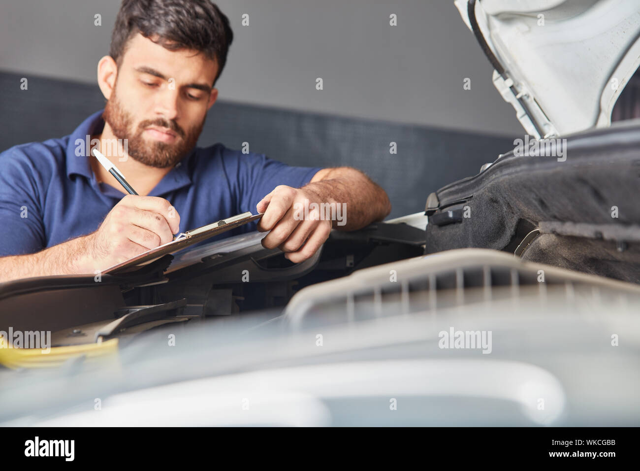 Mechanic in auto repair shop with checklist before repair from the car ...