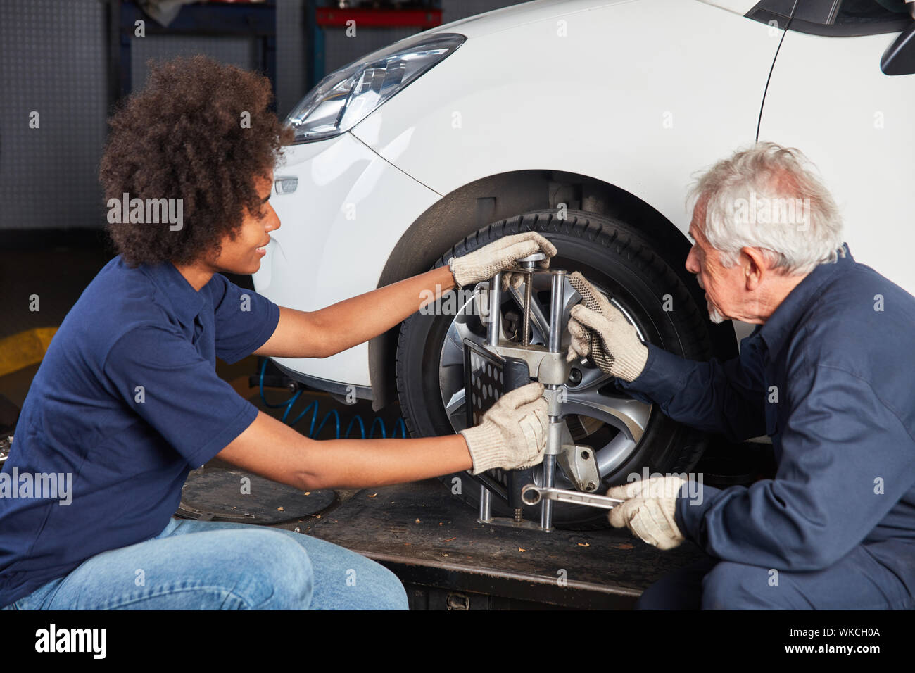 Automotive mechanic team doing a wheel alignment on the chassis in the ...