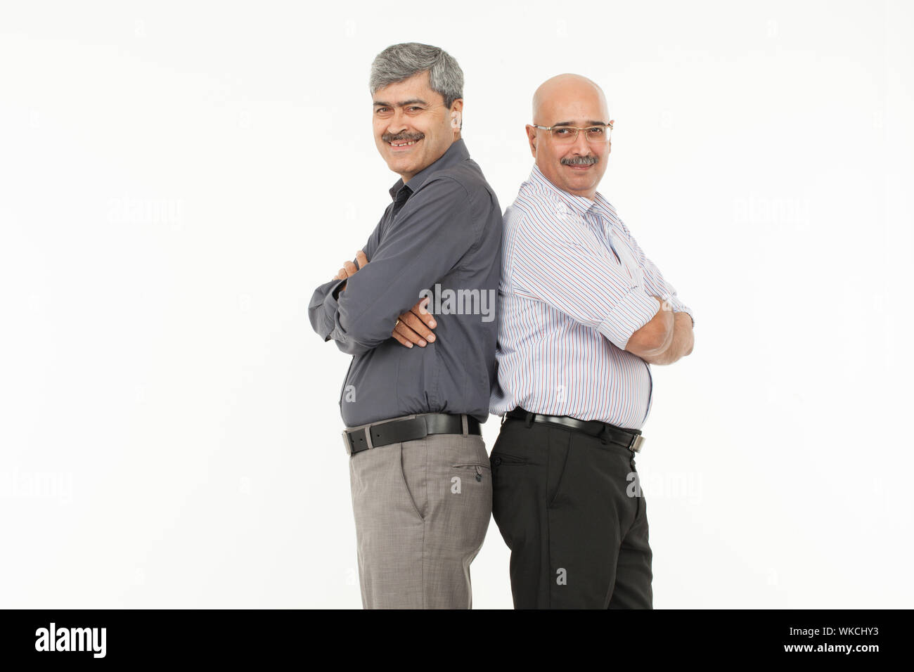 Two business executives standing back to back with his arms crossed ...