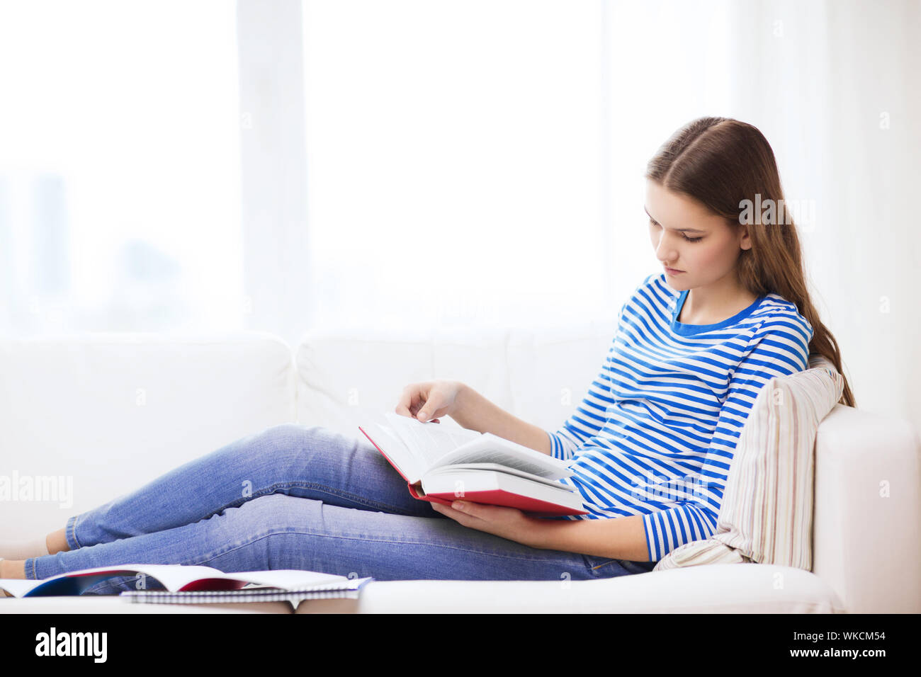 calm teenage girl reading book on couch Stock Photo - Alamy