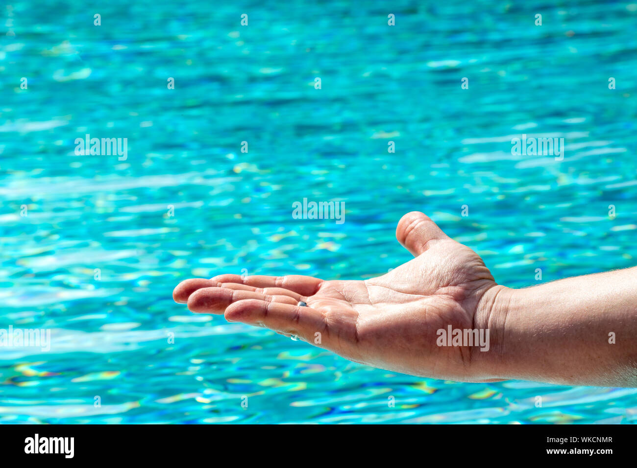 Flat hand against a wavy blue water background with reflections and ...