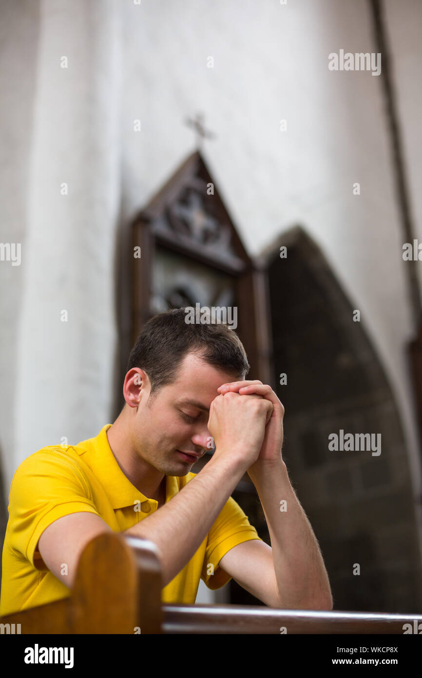 Handsome young man praying in a church Stock Photo - Alamy