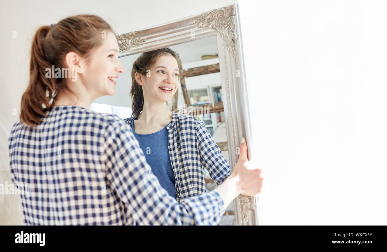 Young woman carries a mirror while moving to her new apartment or her ...