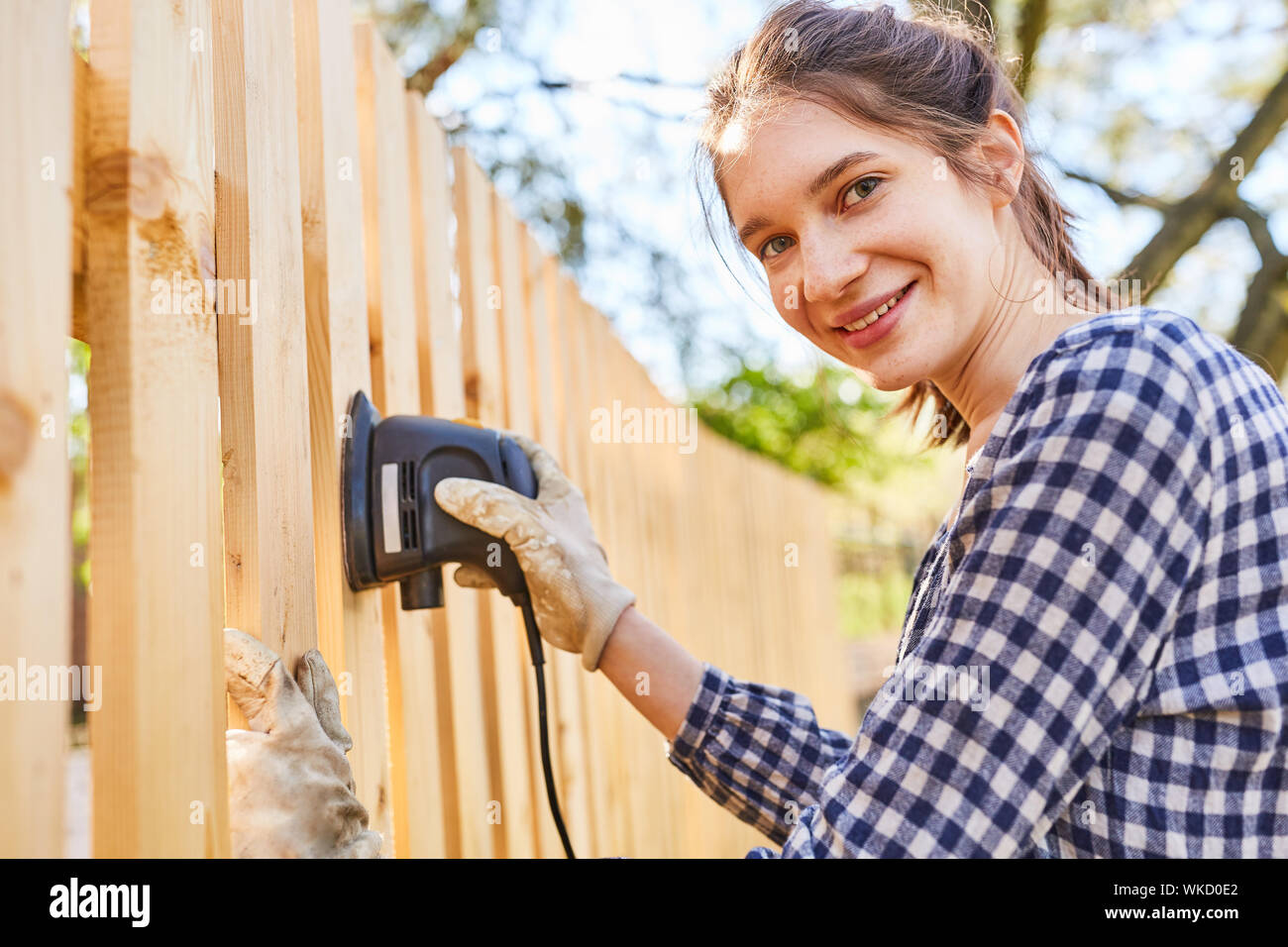 Young woman as a handyman or craftsman apprentice at the fence grind in ...