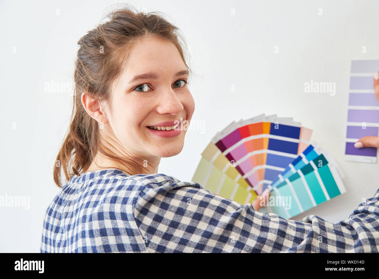 Young woman renovating with color fan while choosing the right wall ...