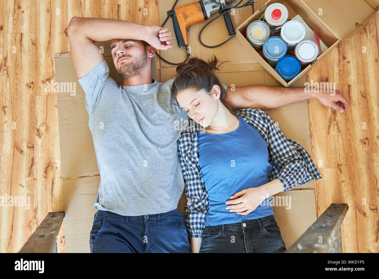 Exhausted young couple falls asleep while renovating after moving on ...