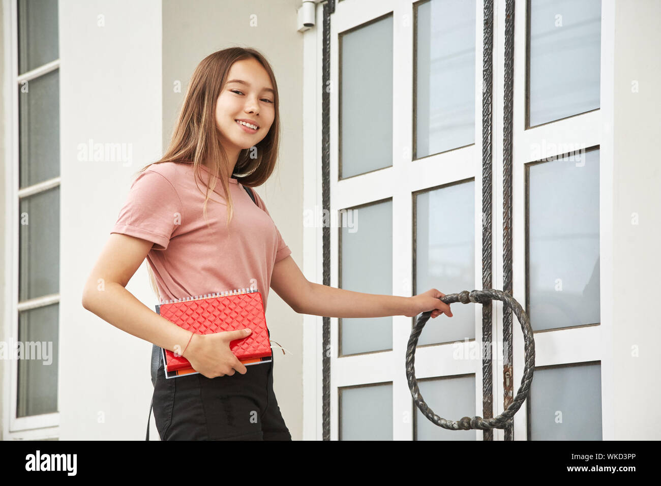 school girl with backpack and educational equipment. Student opening doors of the university ...