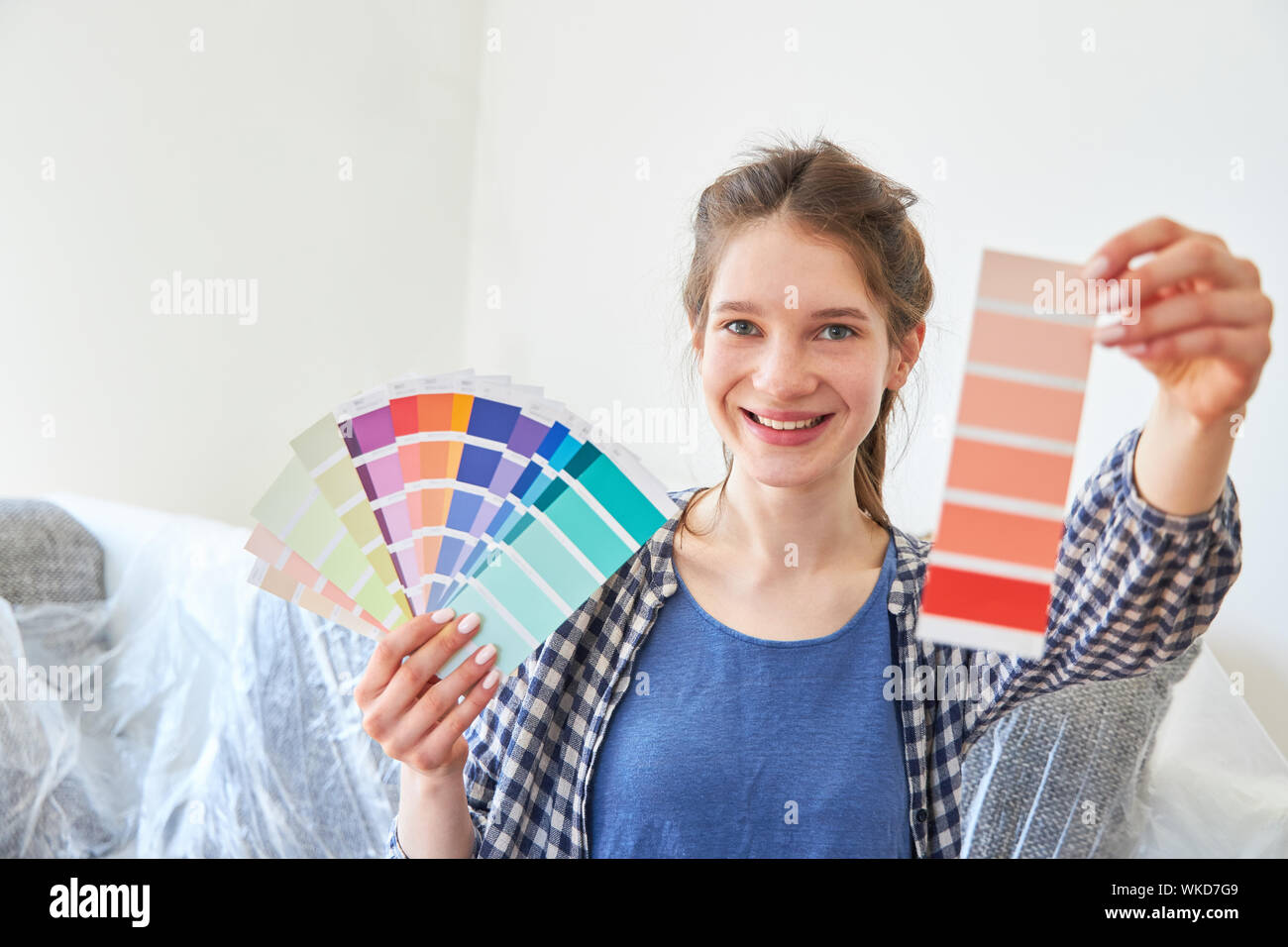 Cheerful young woman with color fan while choosing the right wall color ...