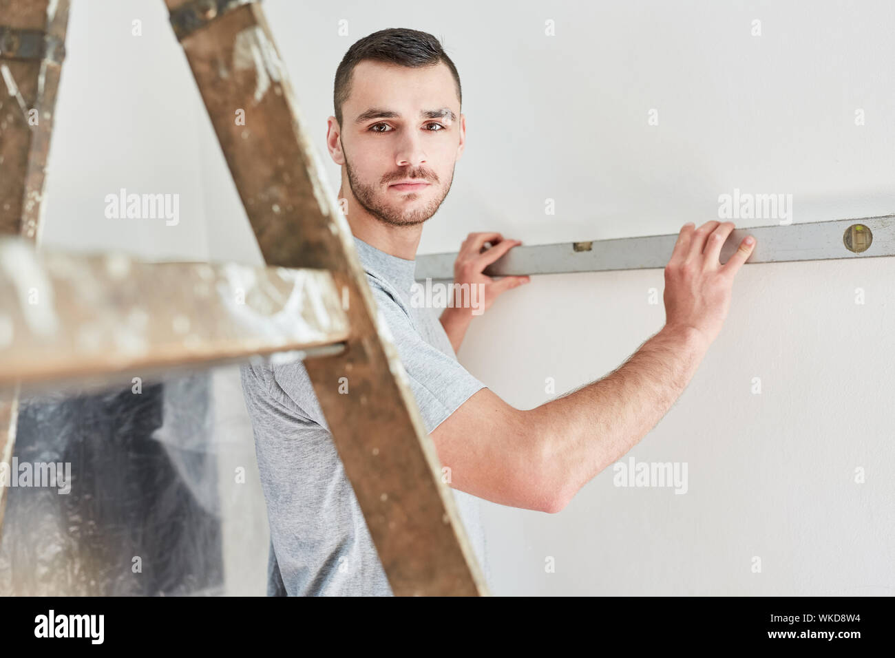 Handyman measuring with spirit level on wall during renovation in new ...