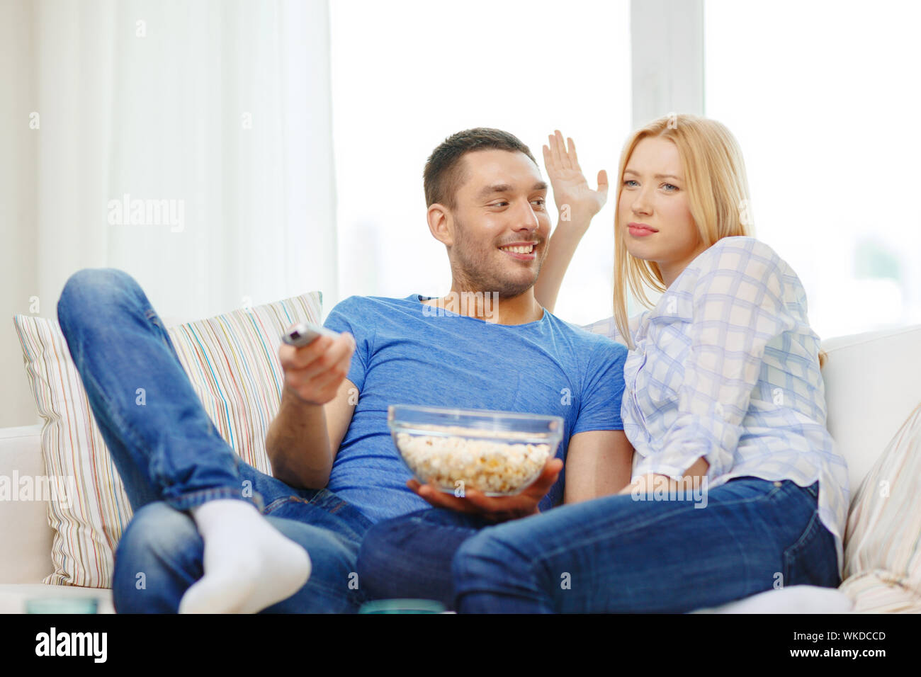 smiling couple with popcorn choosing what to watch Stock Photo - Alamy