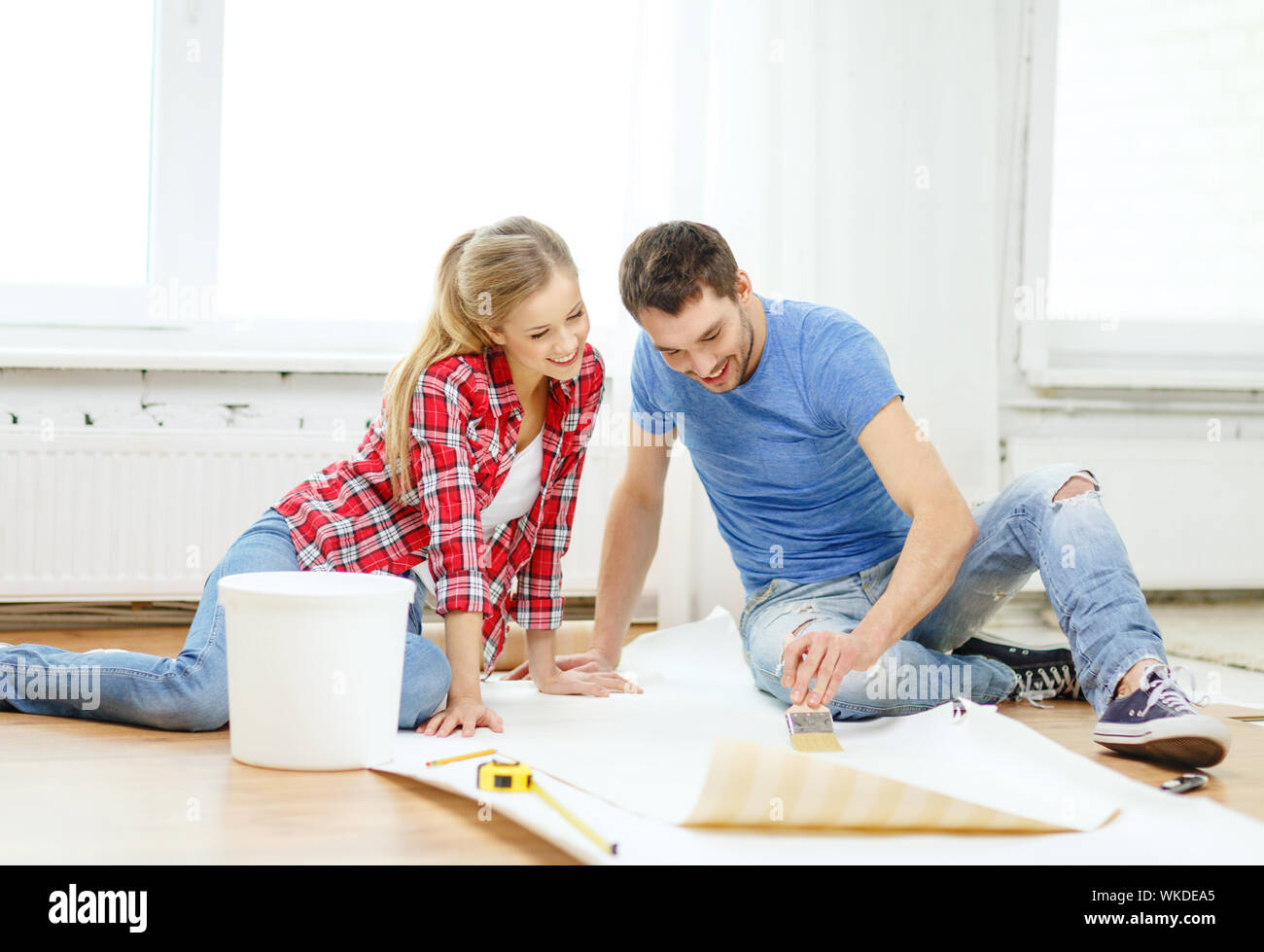 repair, building and home concept - smiling couple smearing wallpaper ...