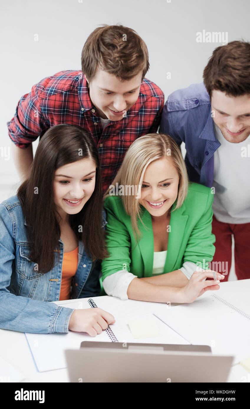 education concept - smiling students looking at laptop at school Stock ...