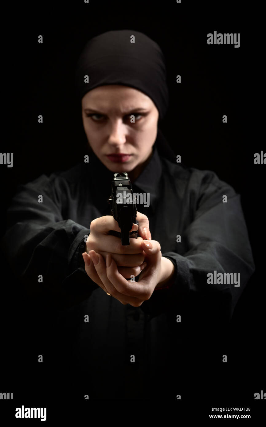 serious girl with gun aiming at camera on black background Stock Photo ...