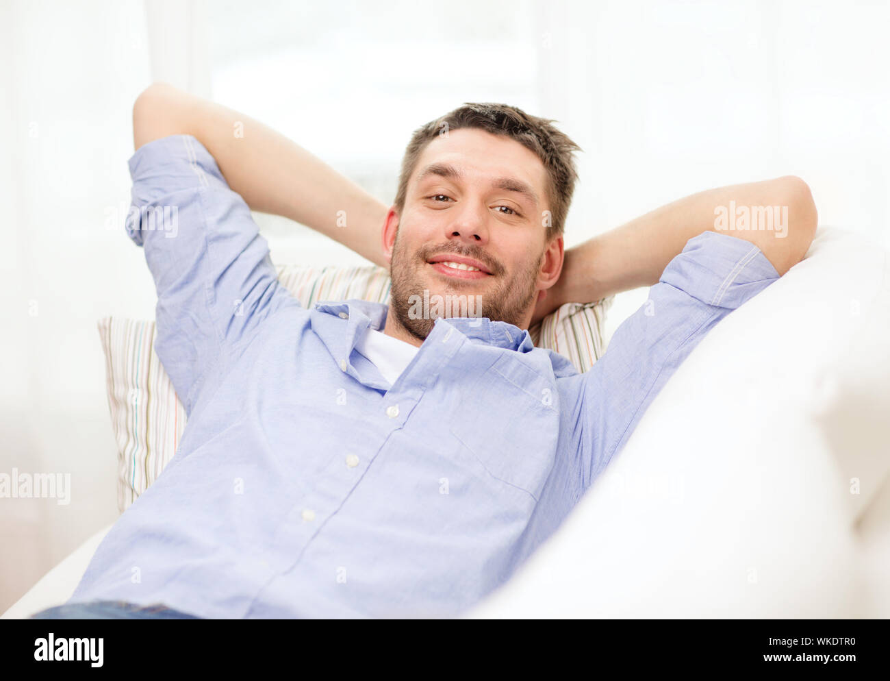 smiling man lying on sofa at home Stock Photo - Alamy