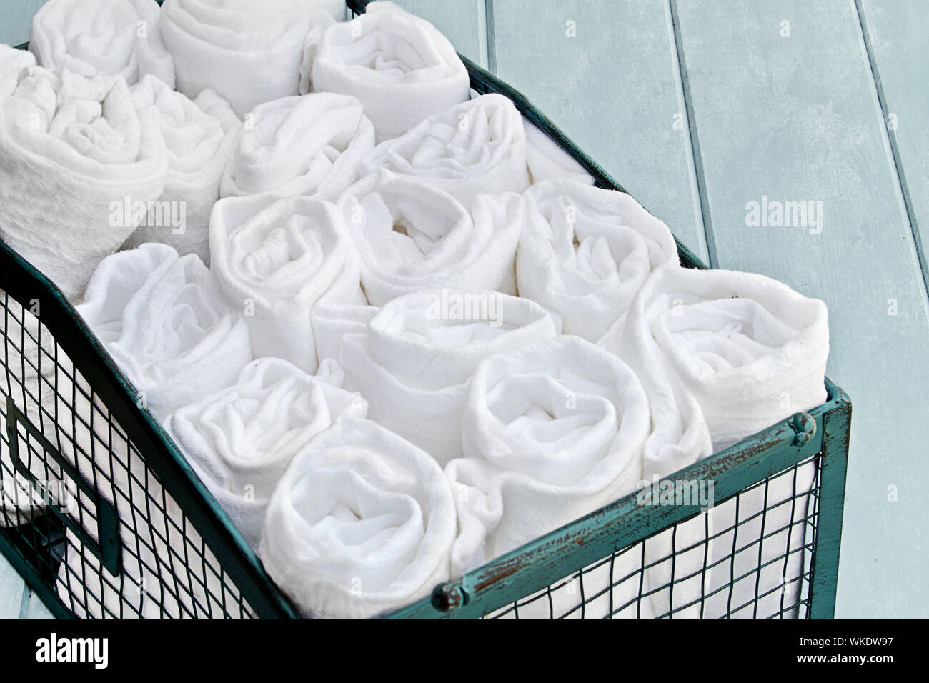 Pretty green basket filled with neatly organized rolled up cleaning ...
