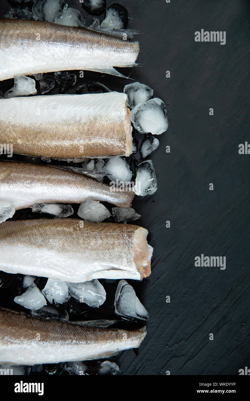 Raw fish hake. Five Raw fish fillet on ice on dark background, food ...