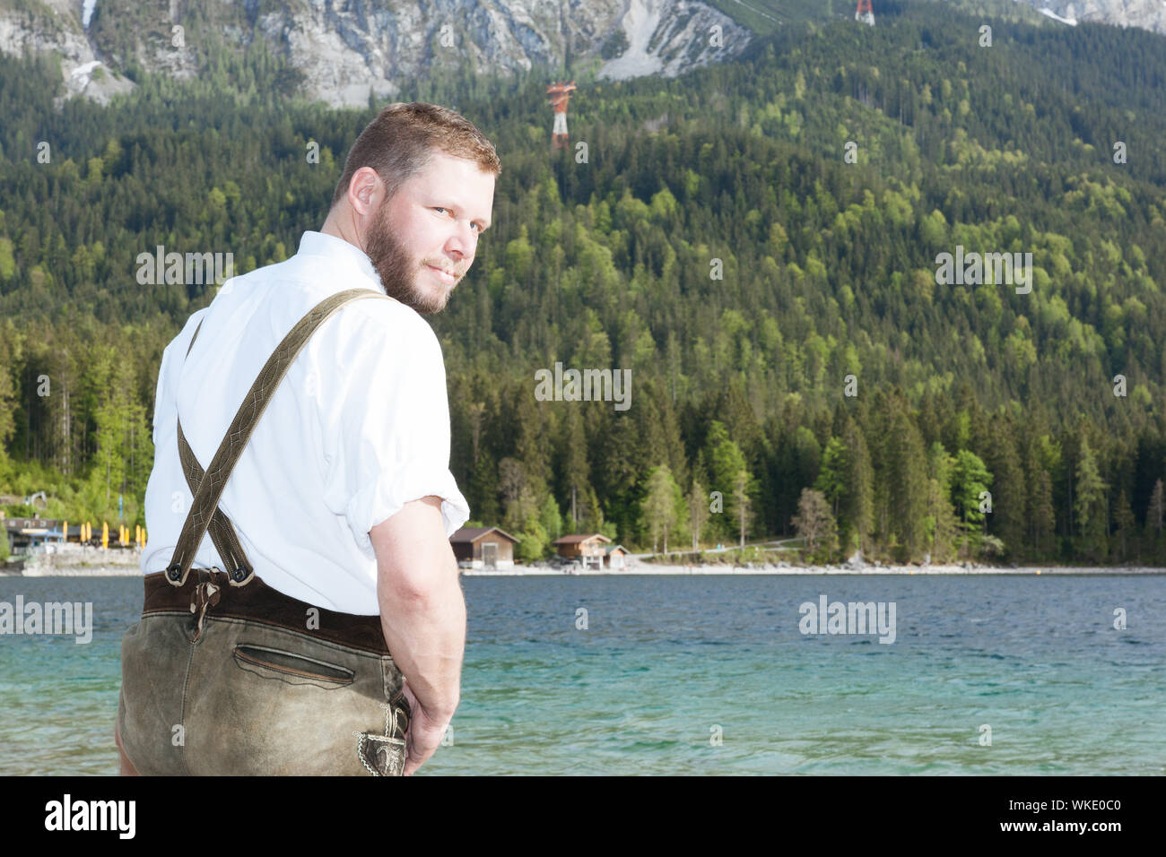 A traditional bavarian man at lake Eibsee with the Zugspitze mountain ...