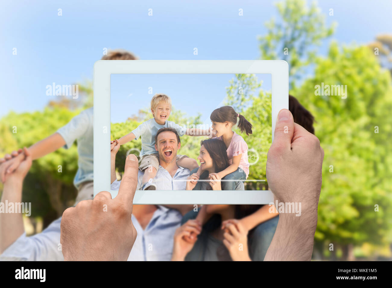 Hand holding tablet pc showing parents giving children a piggyback ...