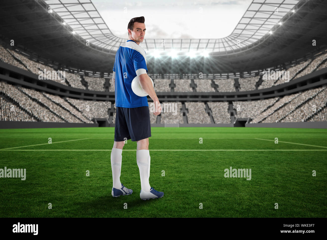 Handsome football player in blue jersey in a vast football stadium with ...