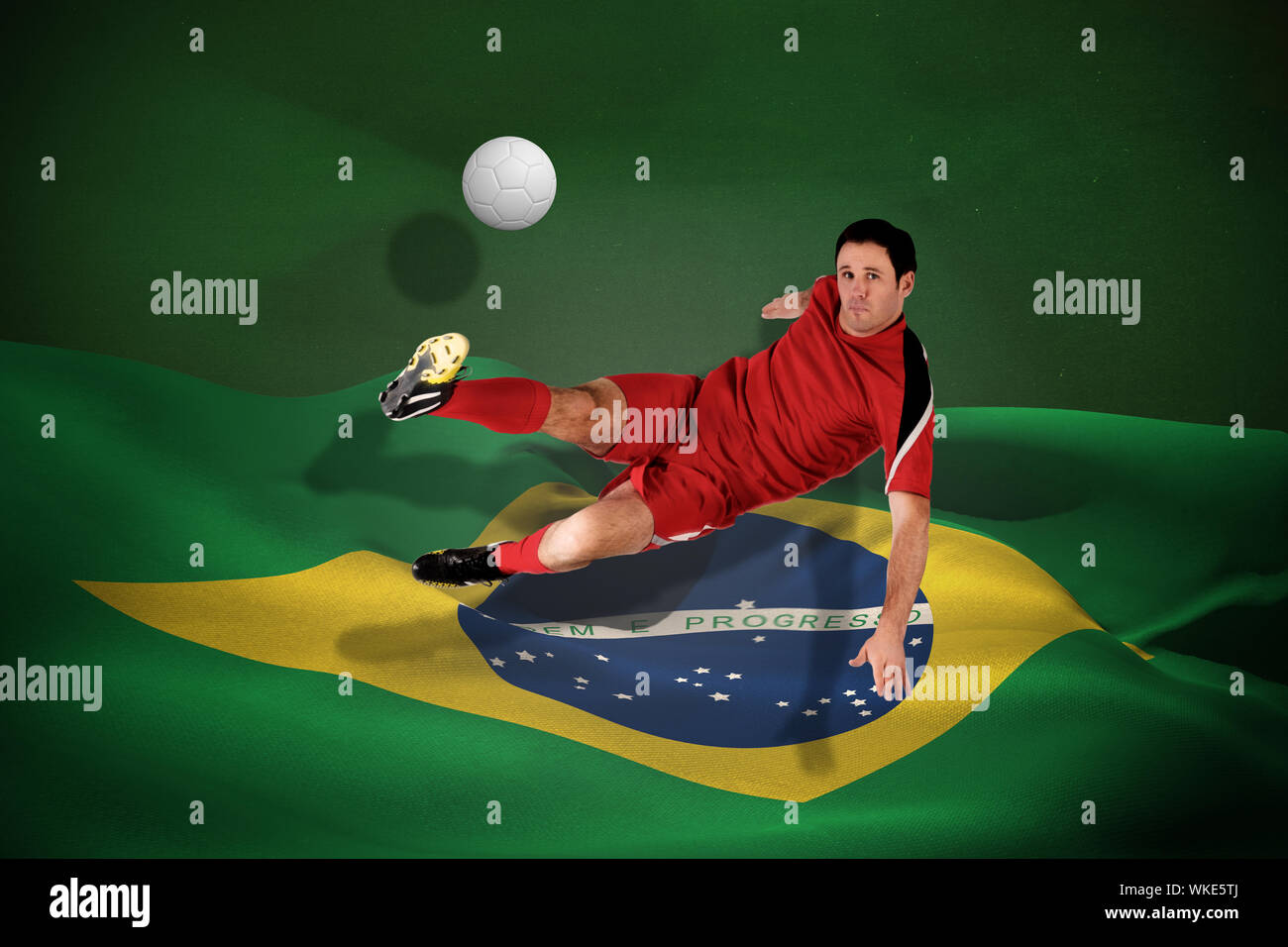 Football player in red kicking against white leather football with ...