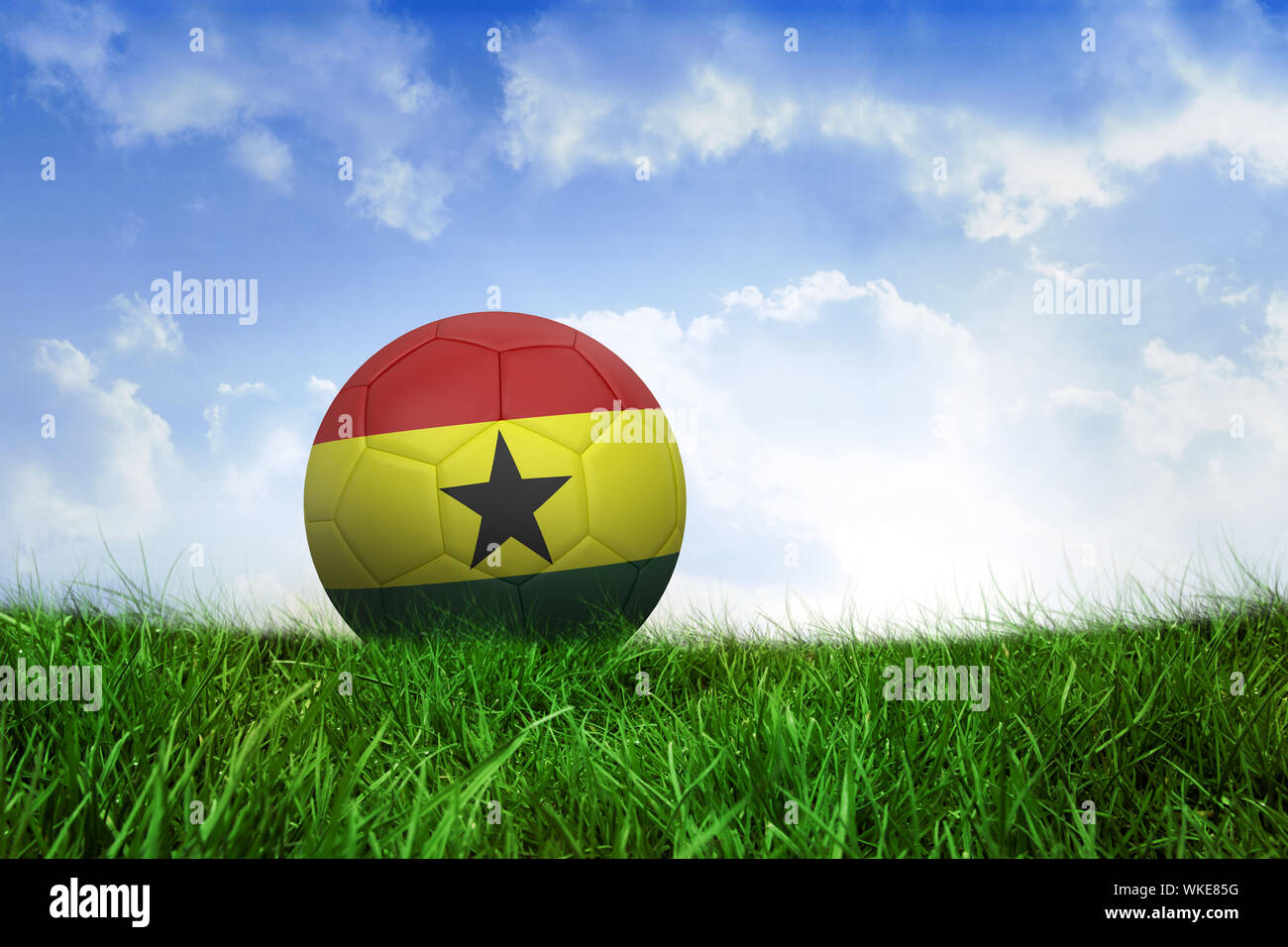 Football in ghana colours on field of grass under blue sky Stock Photo ...